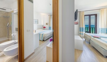 Quarto de hotel moderno com chuveiro, vaso sanitário, cama e varanda com vista.