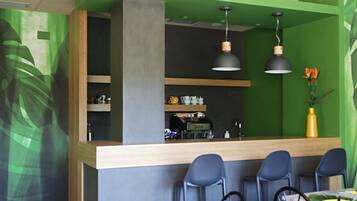 Uma área de bar com balcão, cadeiras e uma máquina de café.
