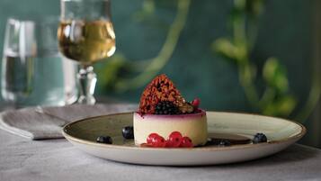 Sobremesa em um prato com frutas vermelhas e um copo de vinho ao fundo.
