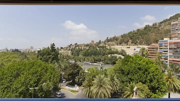 Uma varanda com vista para a paisagem urbana, incluindo edifícios, árvores e uma estrada.