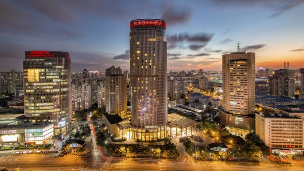 Um edifício alto com fachada de vidro moderna e sinalização iluminada.