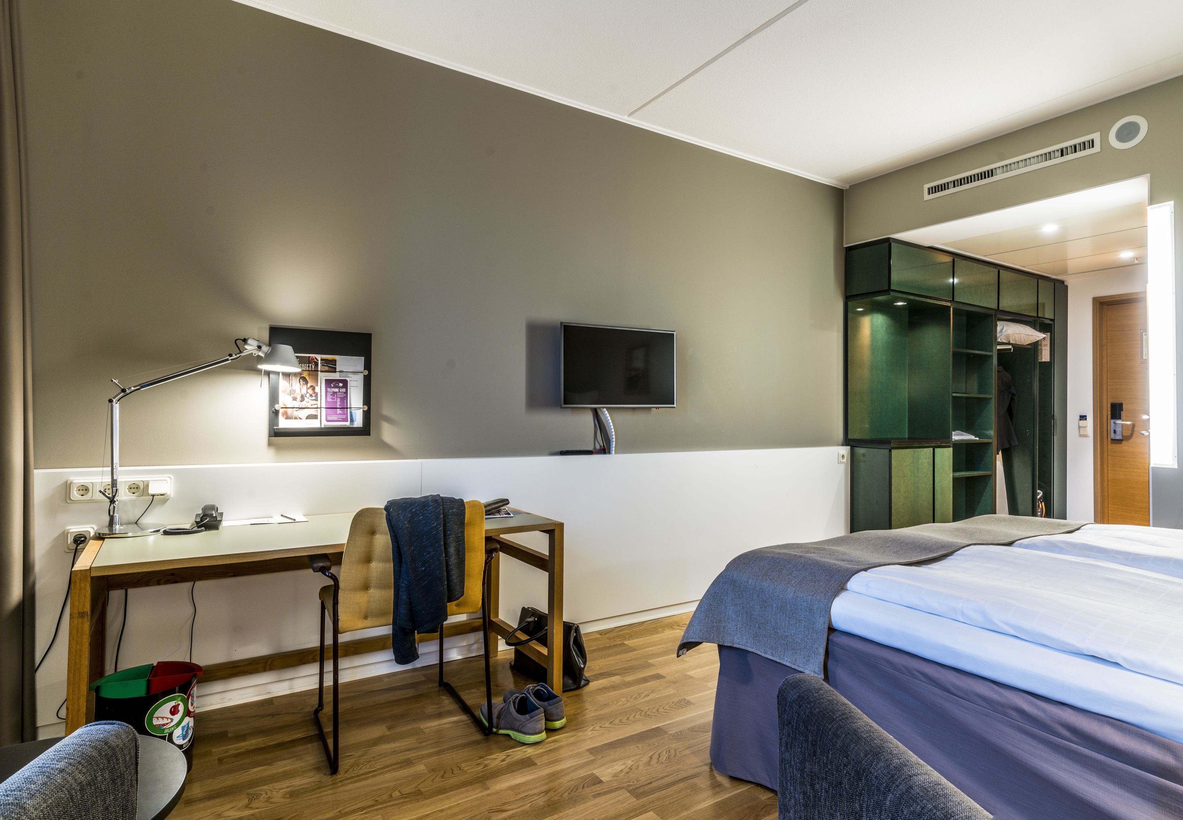 Quarto moderno com escrivaninha, cadeira, televisão e cama.