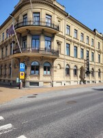 Um edifício histórico com uma varanda de canto imponente, várias janelas e uma placa indicando um hotel chamado "HOTEL DUXIANA".