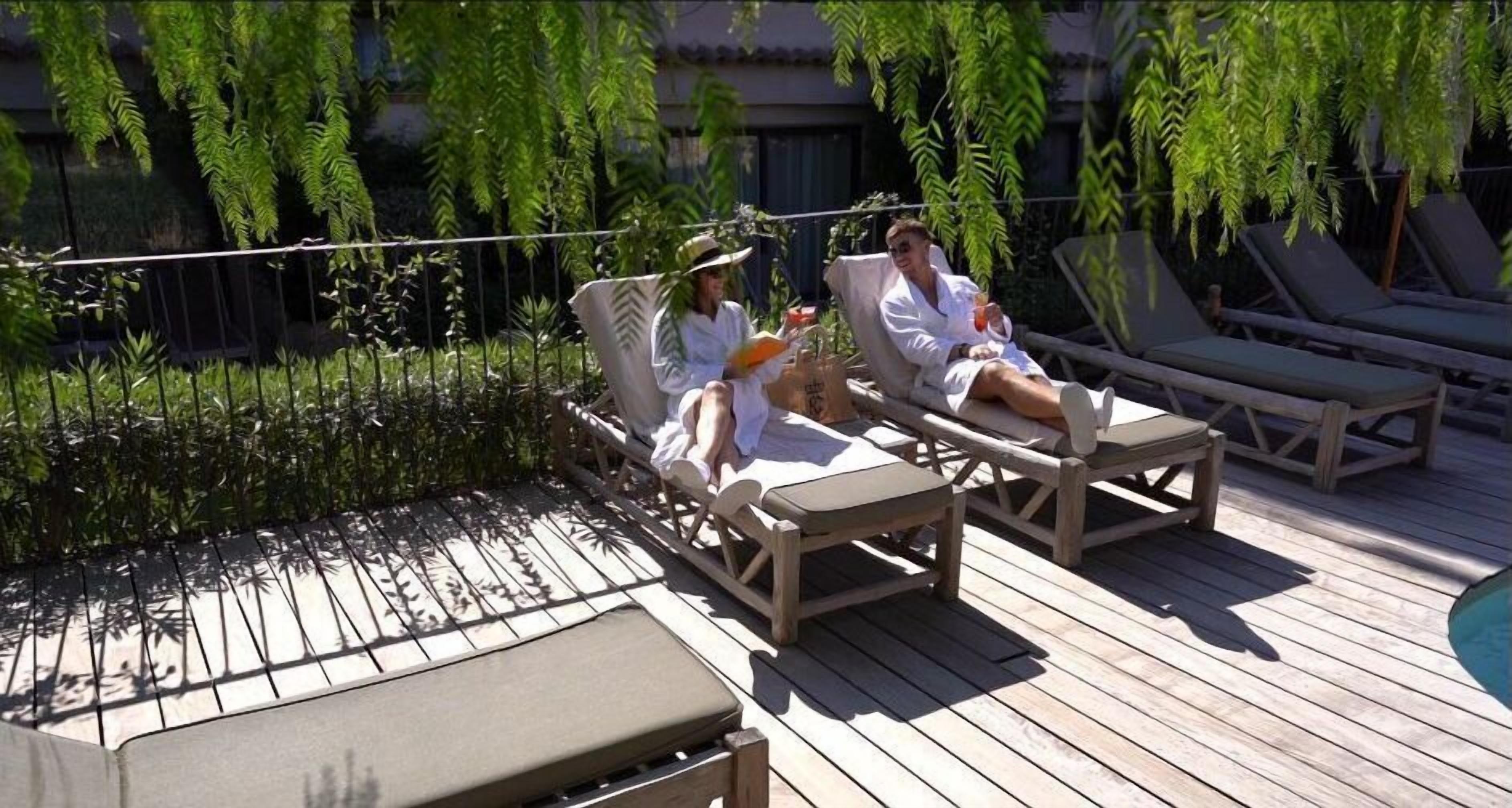 Um deck de madeira com espreguiçadeiras e piscina.