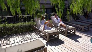 Um deck de madeira com espreguiçadeiras e piscina.
