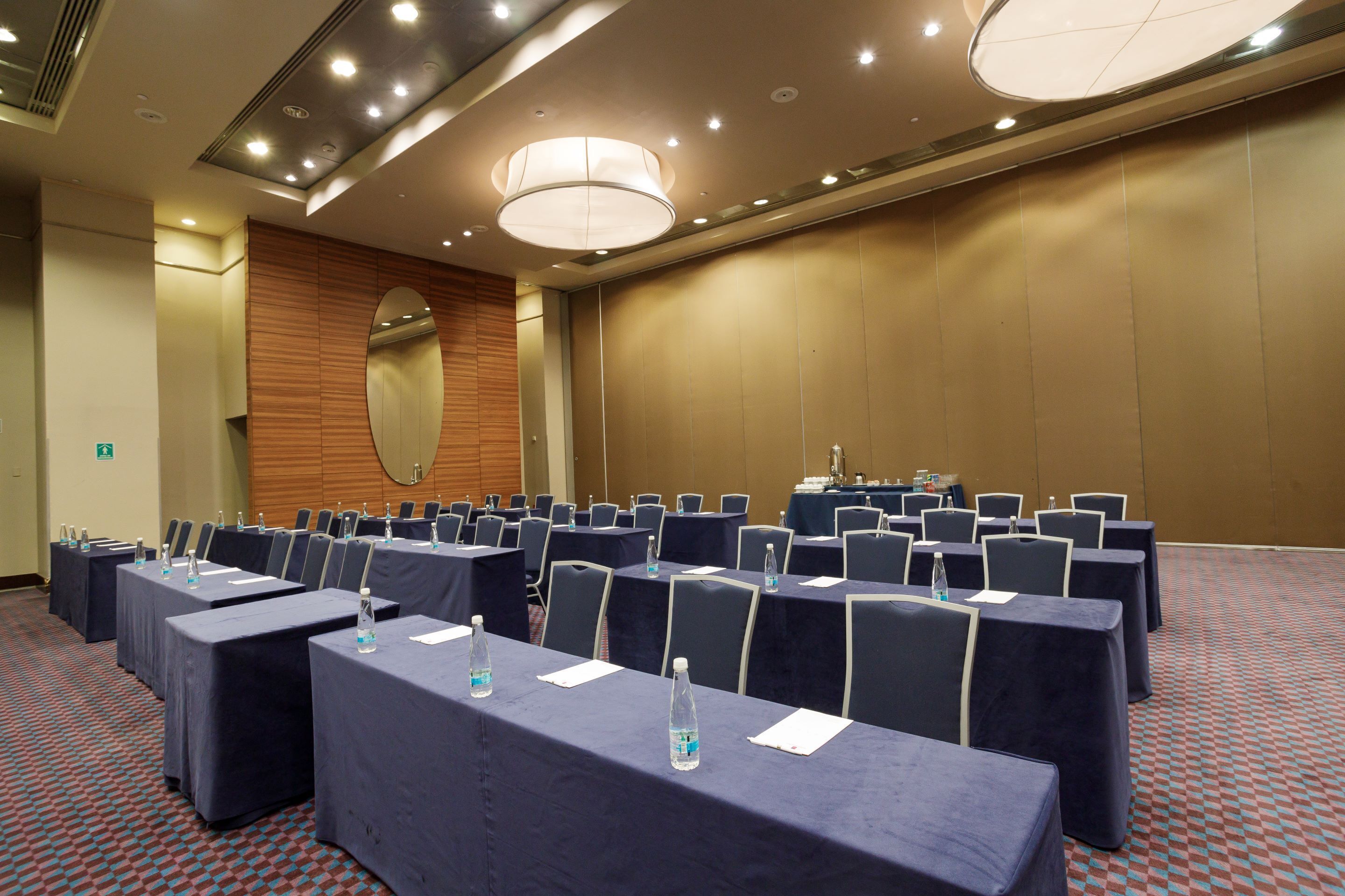Uma sala de conferências com fileiras de mesas, cadeiras e um púlpito.