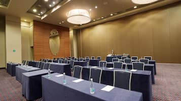 Uma sala de conferências com fileiras de mesas, cadeiras e um púlpito.
