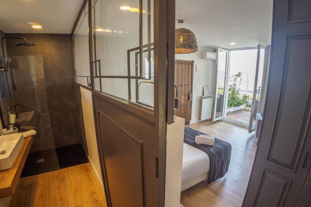 Uma casa de banho moderna com cabine de duche em vidro, toucador de madeira e lavatório independente.