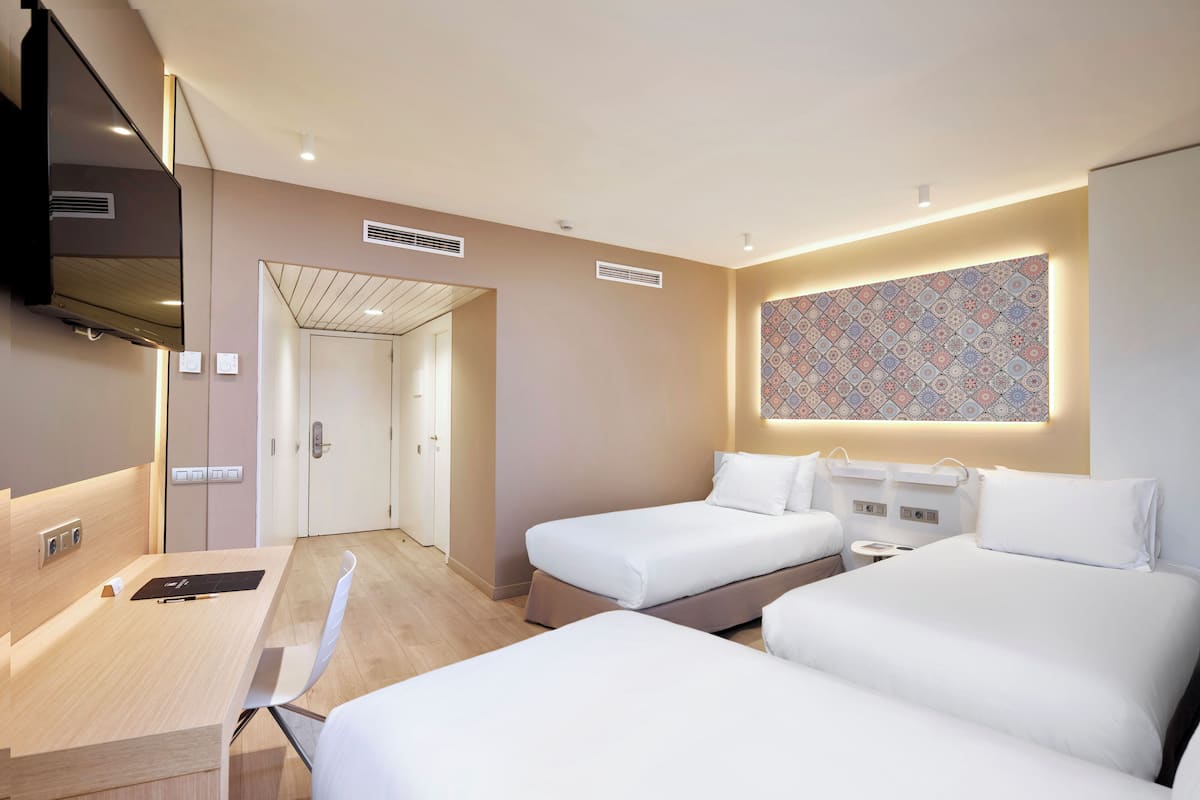 Quarto de hotel com duas camas, uma escrivaninha e uma televisão.