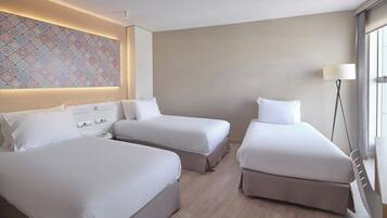 Quarto de hotel com duas camas, uma janela grande e parede estampada.