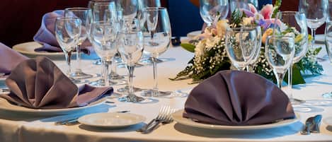 Uma mesa posta para um evento formal, com vários copos de vinho, pratos e talheres.