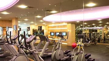 Uma academia com várias esteiras, bicicletas ergométricas e aparelhos de musculação.