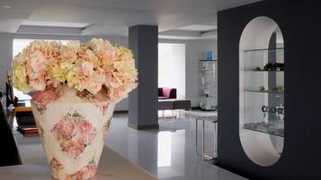 Interior moderno com um vaso de flores sobre uma mesa, uma vitrine de vidro e um elemento circular na parede.