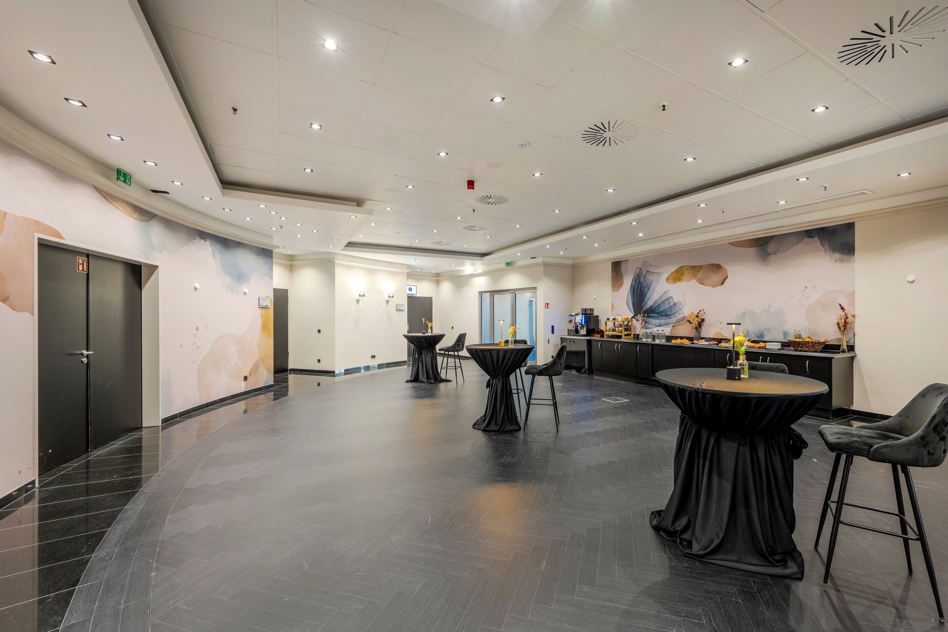 Um amplo hall de hotel com design moderno, com área de recepção, várias mesas e cadeiras.