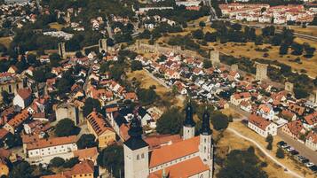 Vista aérea de uma cidade com uma igreja imponente, destacando uma torre grande e uma muralha fortificada.