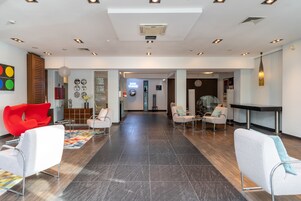 Um hall amplo com assentos modernos, uma área de recepção e vista para o restaurante.