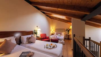 Quarto de hotel com duas camas, teto de madeira, escada e bandeja de café da manhã sobre uma das camas.