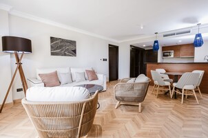 Uma sala de estar moderna com sofá, cadeiras de vime, mesa de centro e área de jantar com cadeiras e mesa.