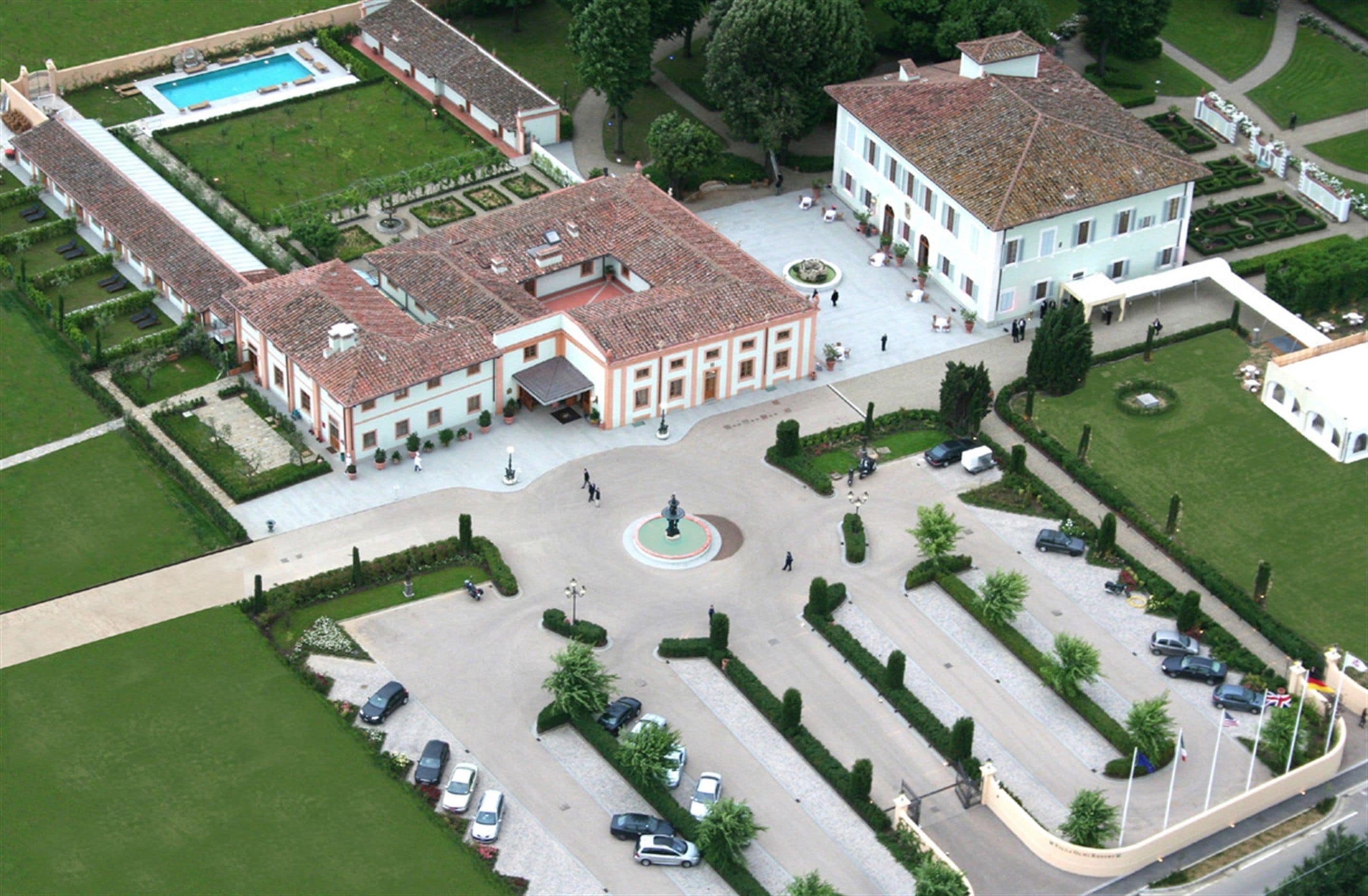 Vista aérea de uma grande propriedade com piscina, vários edifícios e área de estacionamento.