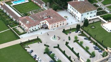 Vista aérea de uma grande propriedade com piscina, vários edifícios e área de estacionamento.