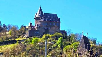 Um castelo histórico numa colina, com edifícios tradicionais em primeiro plano.