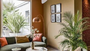 Uma sala de estar moderna com um sofá verde, uma mesa de centro e plantas em vasos.