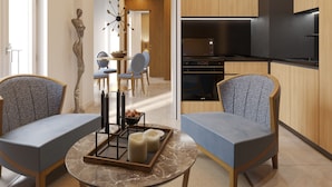 Uma sala de estar moderna com duas poltronas, uma mesa de centro e um espaço de jantar com um candelabro.