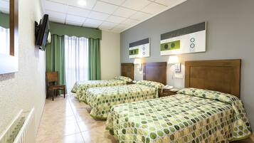 Quarto de hotel com duas camas, uma escrivaninha e uma cadeira.