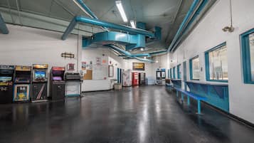 Um espaço amplo e coberto com máquinas de jogos eletrônicos, uma loja Subway de sanduíches e bancos azuis ao longo das paredes.