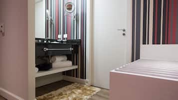 Um banheiro com parede listrada, pia com porta-toalhas, espelho e porta.