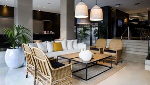 Um lobby moderno com sofá, cadeiras, mesa de centro e luminárias pendentes.
