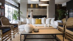 Um lobby moderno com móveis de vime, um sofá branco e grandes vasos em uma mesa de centro.
