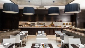 Restaurante moderno com área de bar central, várias mesas de jantar e iluminação pendente.