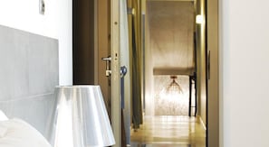 Corredor de hotel com luminária, porta e lustre.