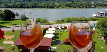 Duas taças de vinho com vista para um lago e área de estar ao ar livre.