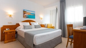 Quarto de hotel com cama, mesas de cabeceira, escrivaninha e cadeira.