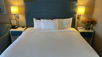 Quarto de hotel com uma cama grande, duas mesas de cabeceira, uma cabeceira e duas luminárias.