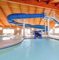 Piscina interna com escorregador azul e escada.