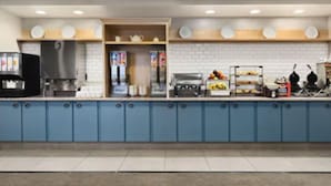 Uma cozinha moderna com armários azuis, uma máquina de café e diversos alimentos à mostra.