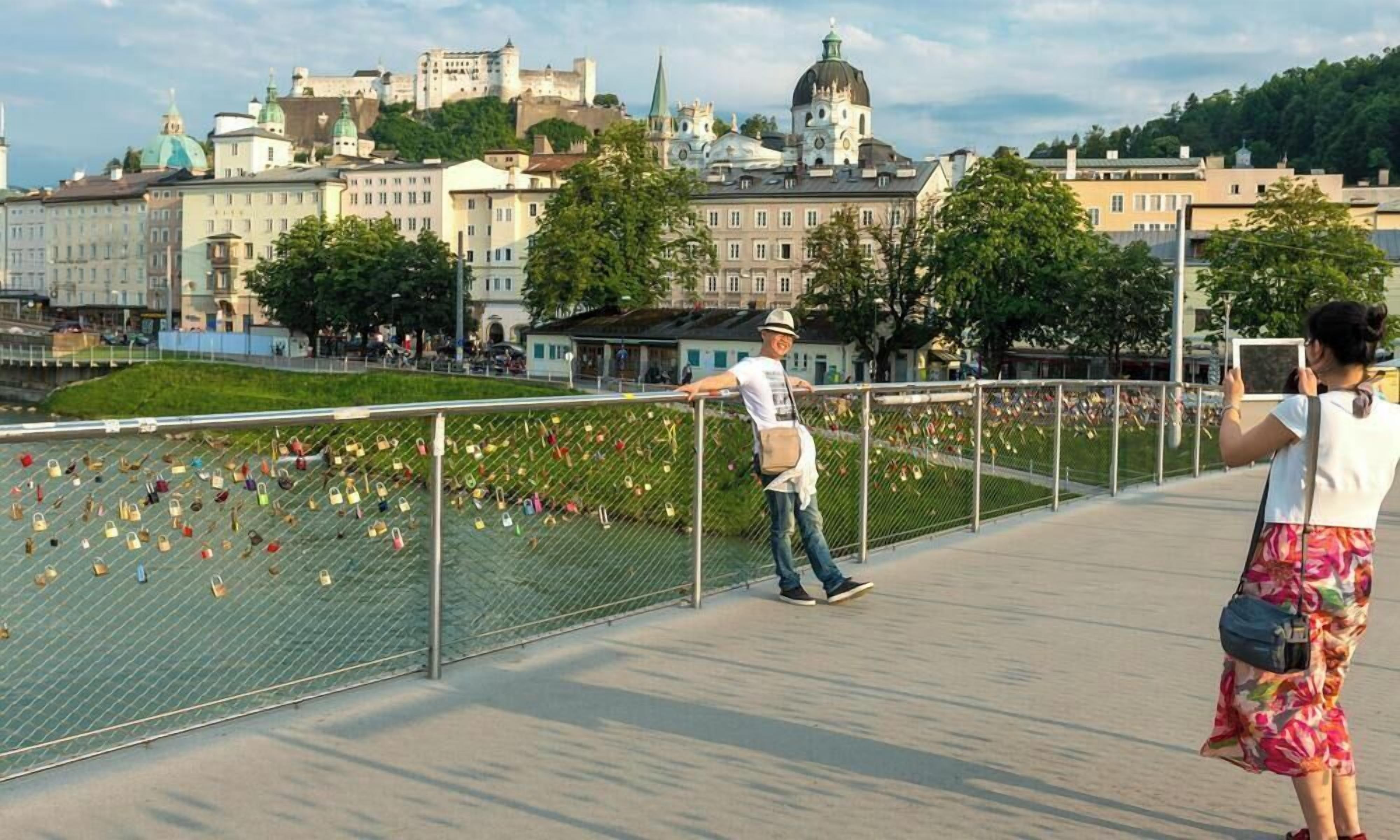 Uma ponte para pedestres com vista para edifícios históricos e um rio.