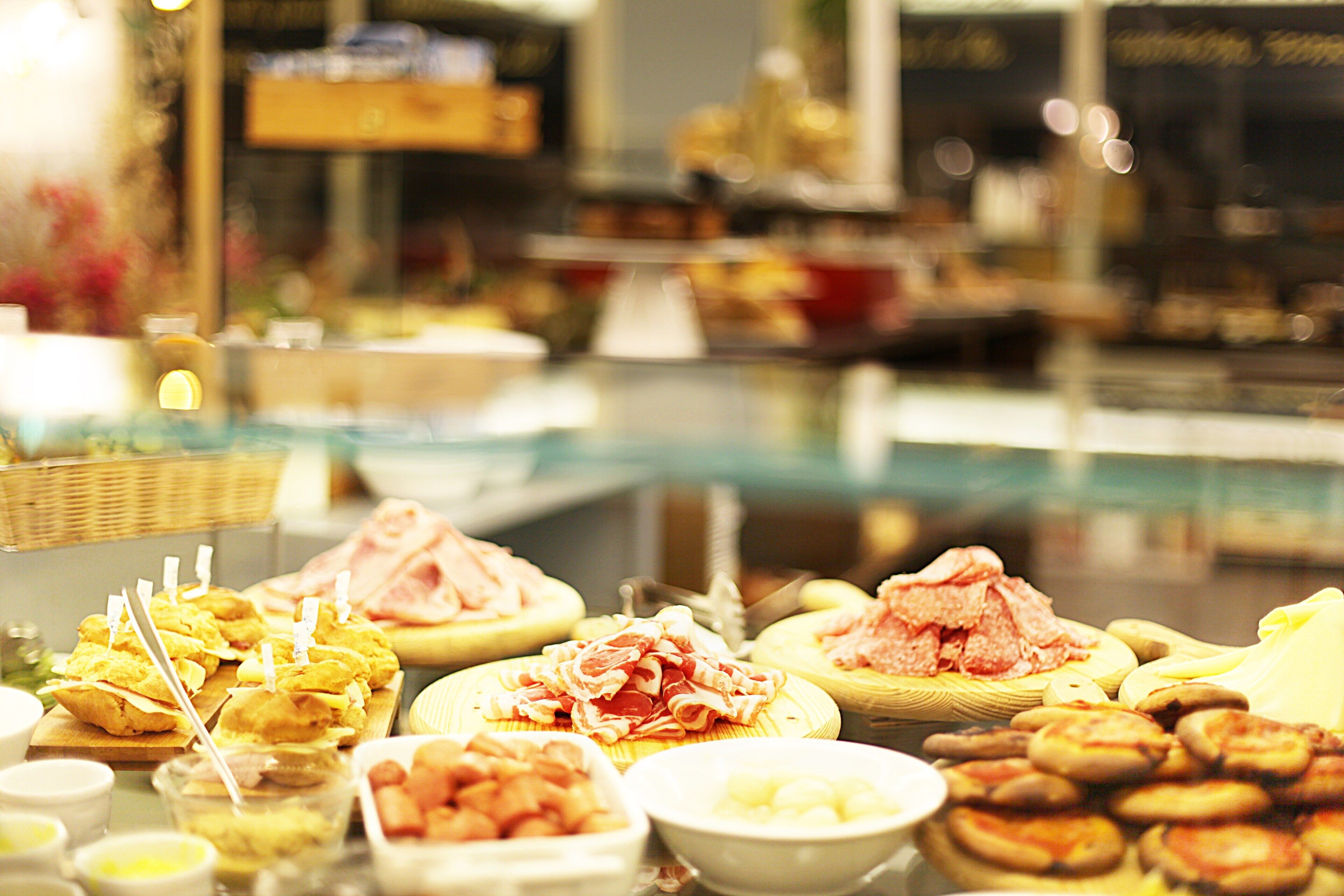 Buffet com diversos alimentos, incluindo carnes, queijos e doces.