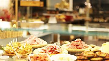 Buffet com diversos alimentos, incluindo carnes, queijos e doces.