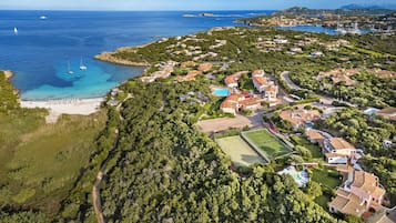 Vista aérea de uma área residencial costeira, com casas, uma praia e um mar azul cristalino.