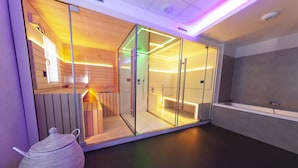 Um spa moderno com divisória de vidro, piso de madeira e área de chuveiro visível.