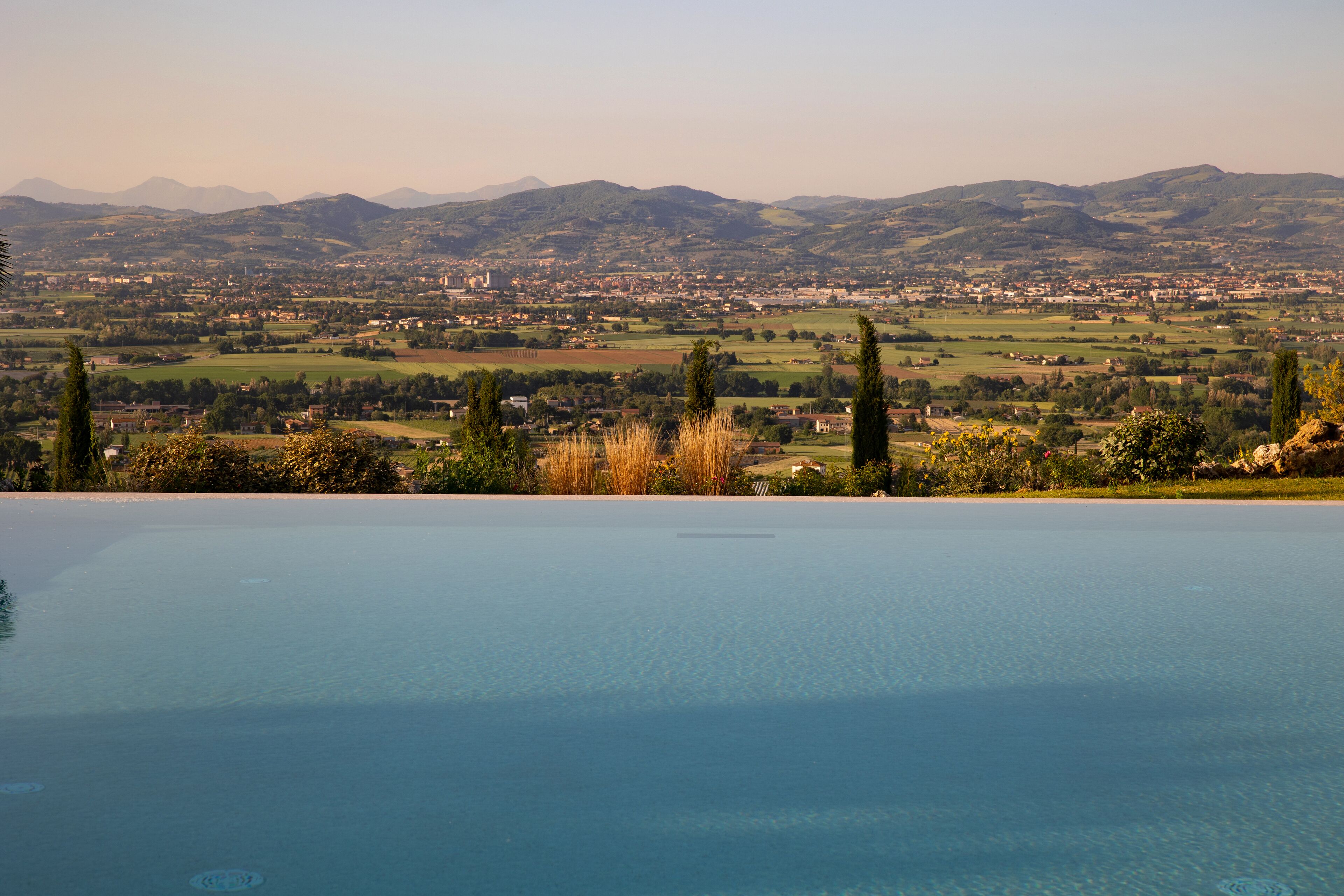 Piscina com vista para uma cidade e montanhas ao fundo.
