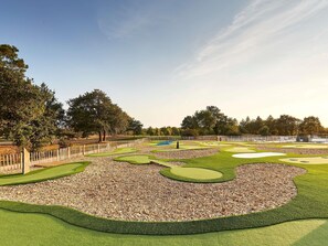 Um campo de golfe com cerca de madeira, armadilhas de areia e mastro de sinalização.