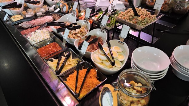 Buffet com diversos alimentos, incluindo carnes, queijos e saladas.