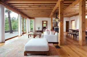 Um quarto amplo com teto de madeira, janelas grandes, um sofá, uma mesa e um espaço para refeições.