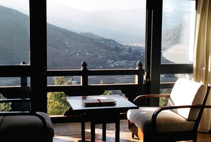 Quarto com vista para um vale, uma mesa com um livro e uma cadeira.