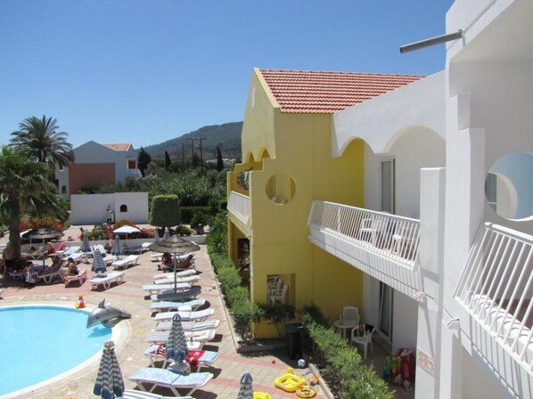 Pátio de hotel com piscina, espreguiçadeiras e área de recreação infantil.